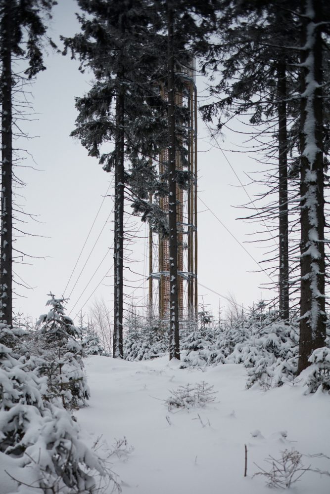 a lookout tower rises above the forested mountains of a czech ski area