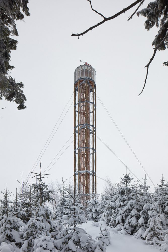 a lookout tower rises above the forested mountains of a czech ski area