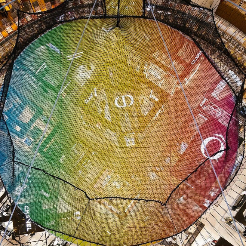 suspended rainbow net stretches in the middle of galeries lafayette paris