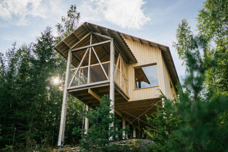 wooden cabin on stilts is perched on mountainous scenery in sweden