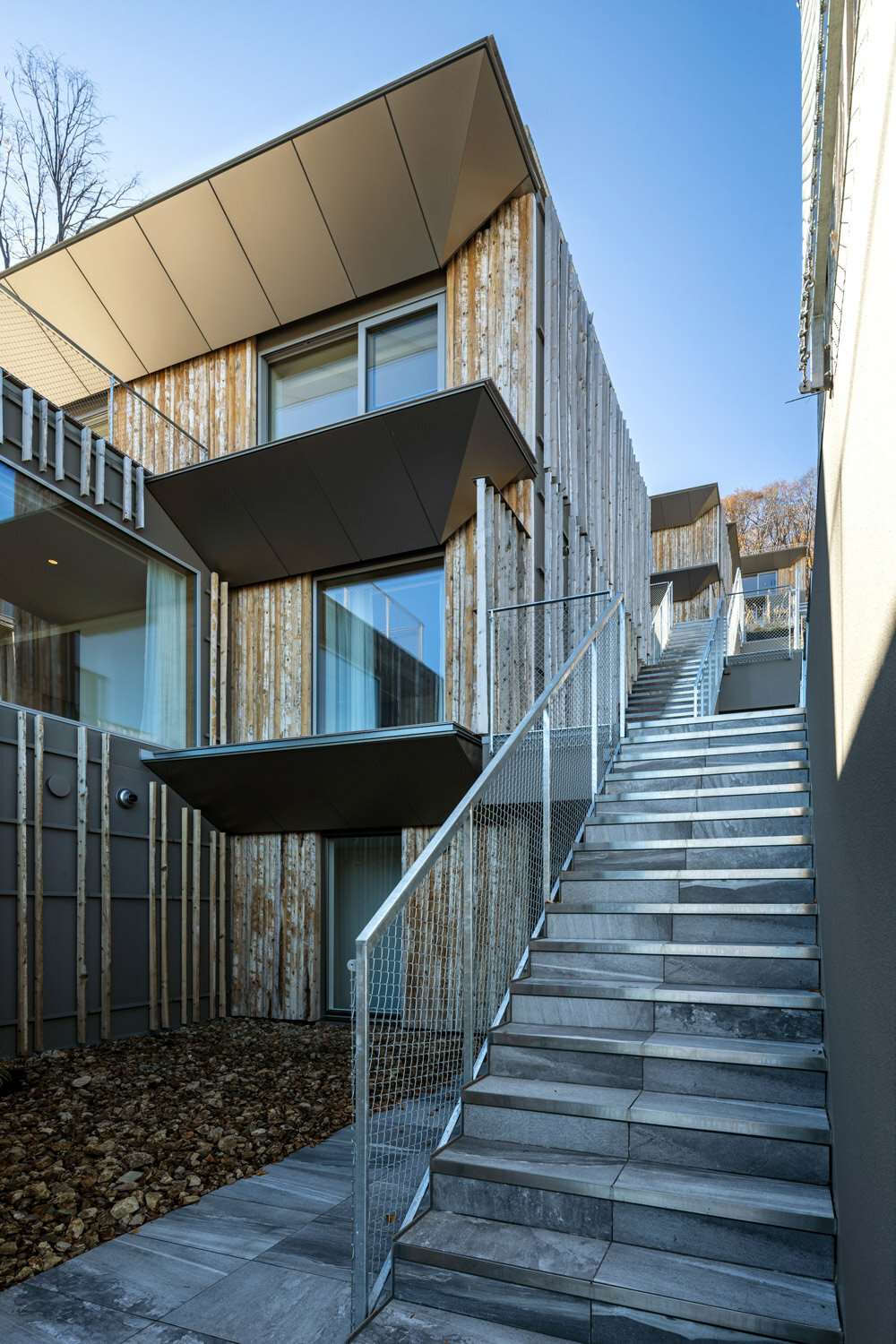 kengo kuma's staggered house units climb a mountainside in japan