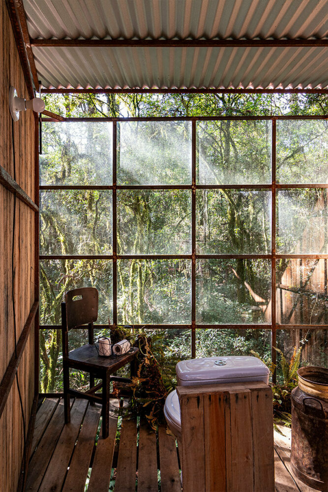 a set of wooden restroom cabins peeks through the treetops of native ...