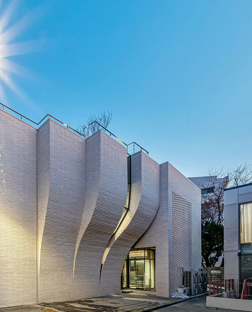 a curved brick wall ripples across LESS architects' office building ...