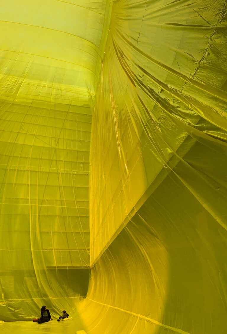 yellow inflatable installation squeezes into void space in barcelona