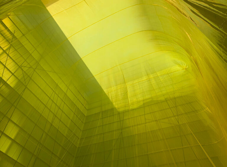 yellow inflatable installation squeezes into void space in barcelona