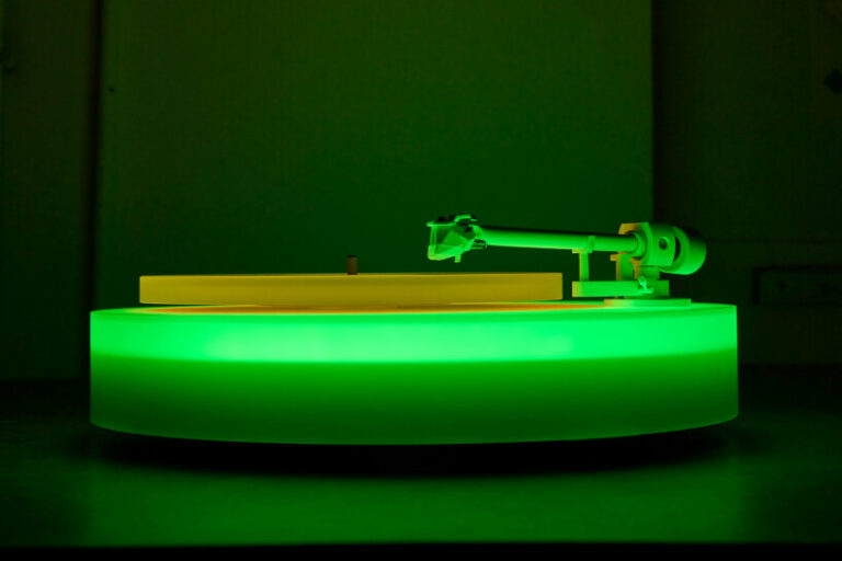 brian eno’s turntable II glows in different acrylic neon lights as the vinyl record plays