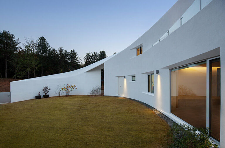 curvilinear house in korea sweeps to the ground with fluid facade