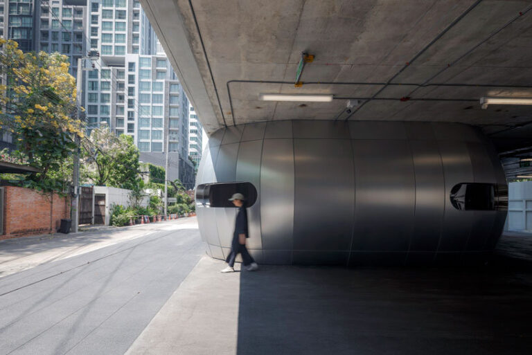ASWA installs steel entrance along curved concrete panel facade in bangkok
