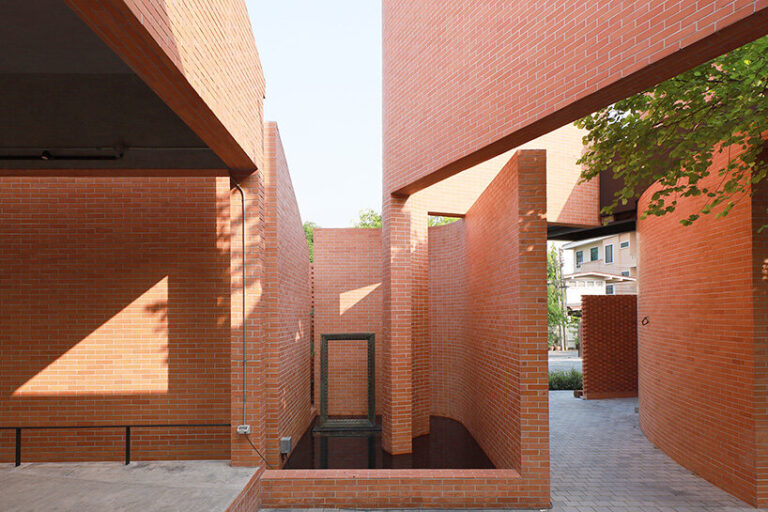 brick wall envelops volume matrix studio's building in bangkok