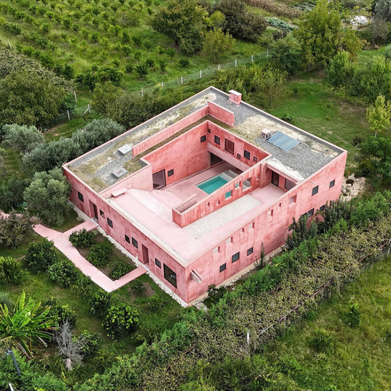 square openings punctuate the facade of red house in albania