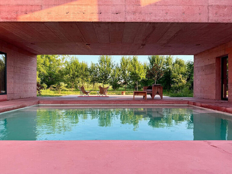 square openings punctuate the facade of red house in albania